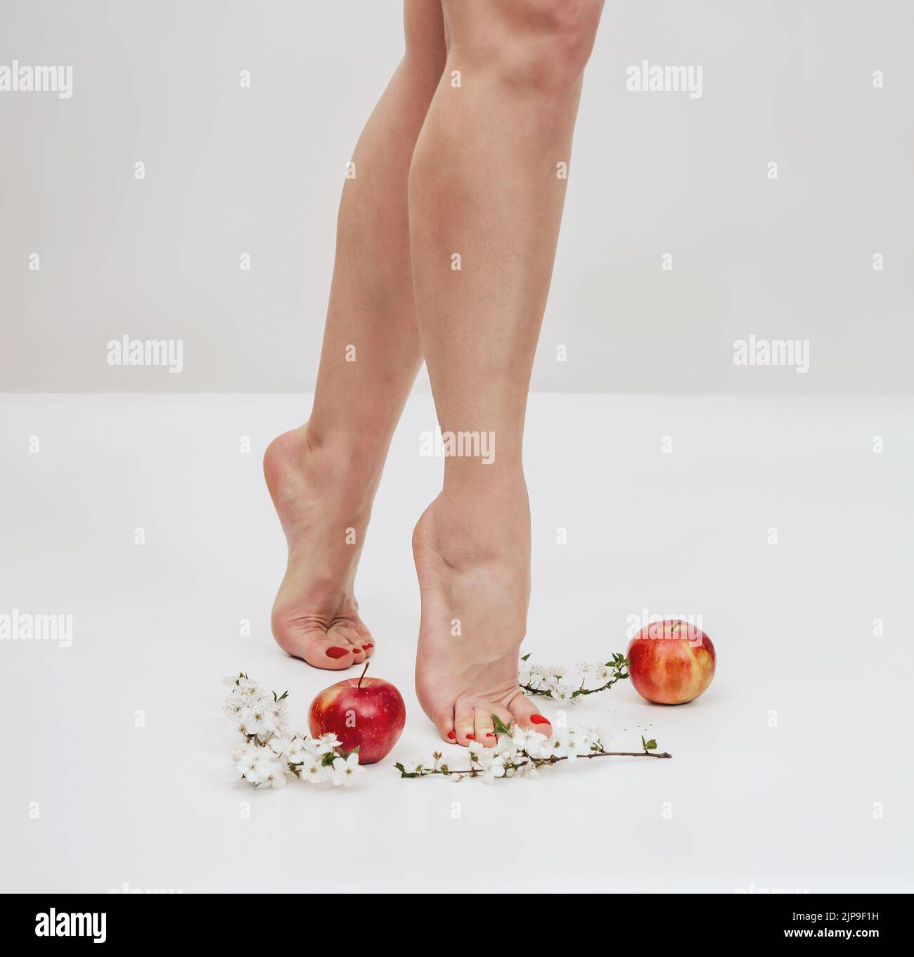 Barefoot female feet on white background with apples and flowers Stock ...