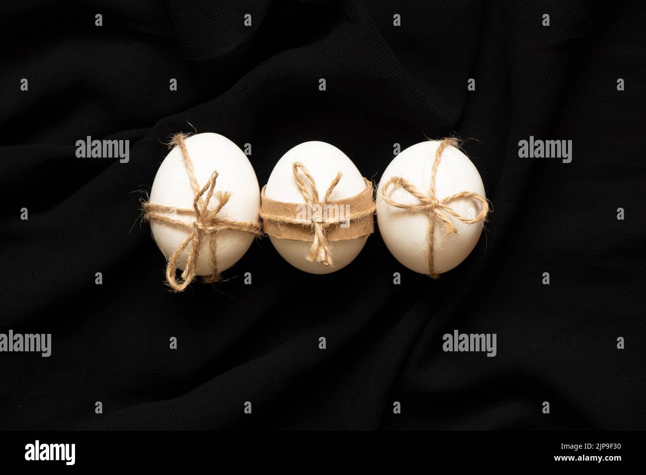 Chicken eggs tied with a rope lie on a black background, Easter holiday ...