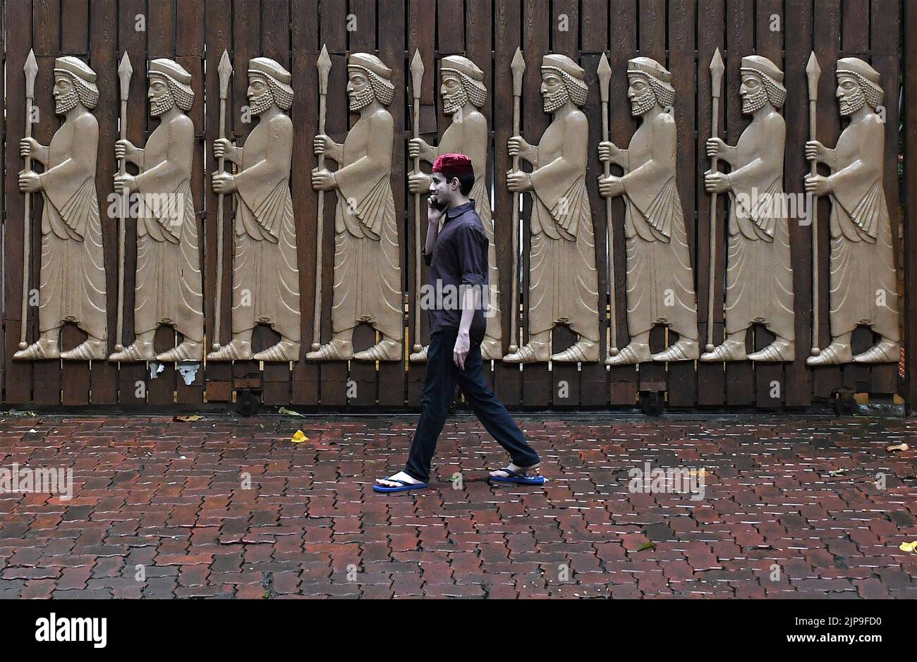 Mumbai, India. 16th Aug, 2022. A Parsi man walks past the carvings of ...