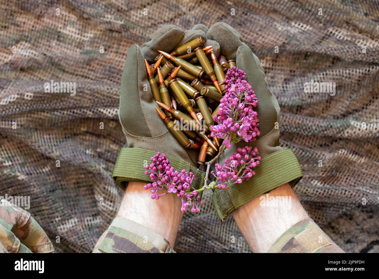Ukrainian soldier in gloves holds bullets from a machine gun on a ...