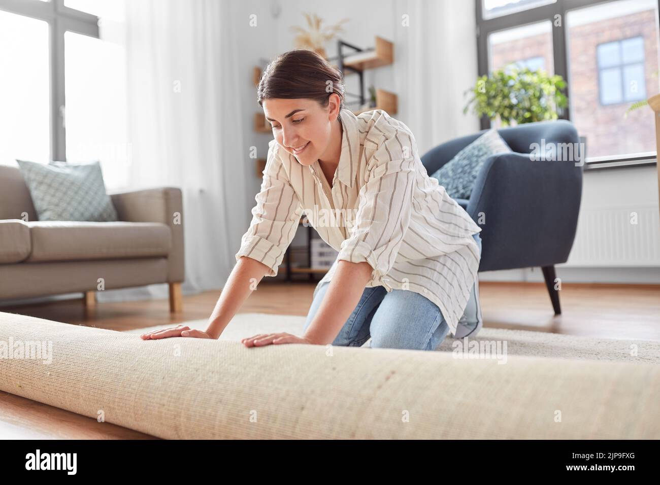 young woman unfolding carpet at home Stock Photo - Alamy