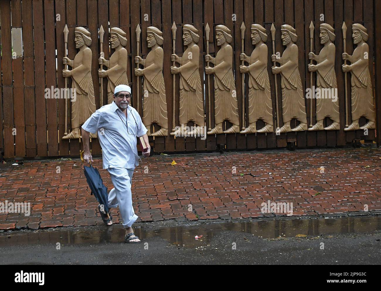 Mumbai, India. 16th Aug, 2022. A Parsi man holds an umbrella and a book ...