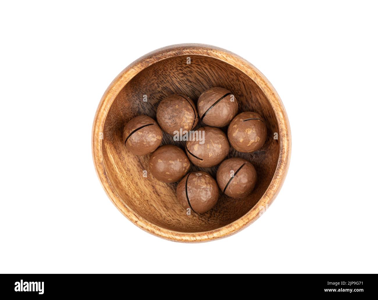 Top view of a few unpeeled macadamia nuts in a bowl over a white ...