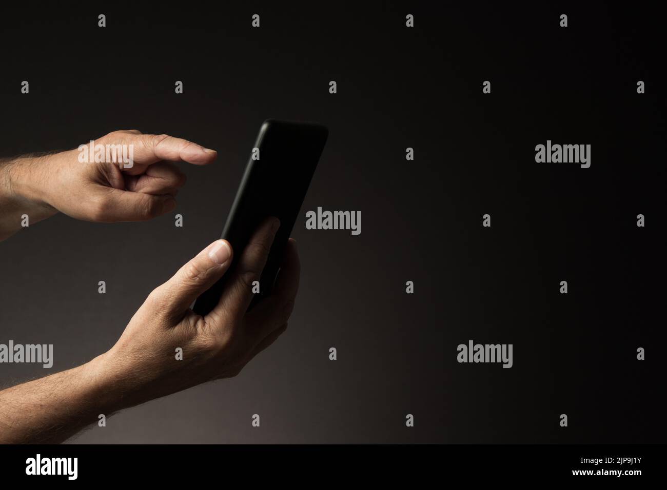 Side view of man's hands holding smart phone with finger touching ...