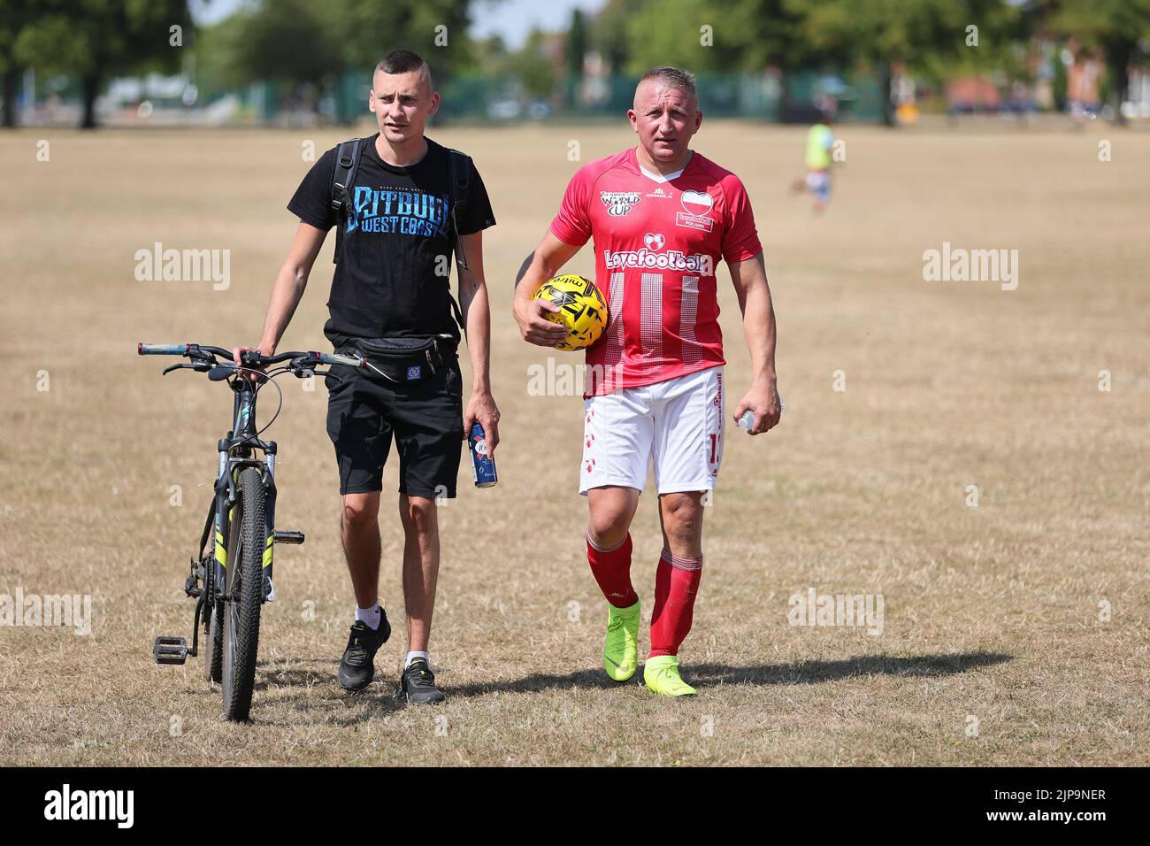 Friends walk on scorched grass due to the UKs drought during an ...