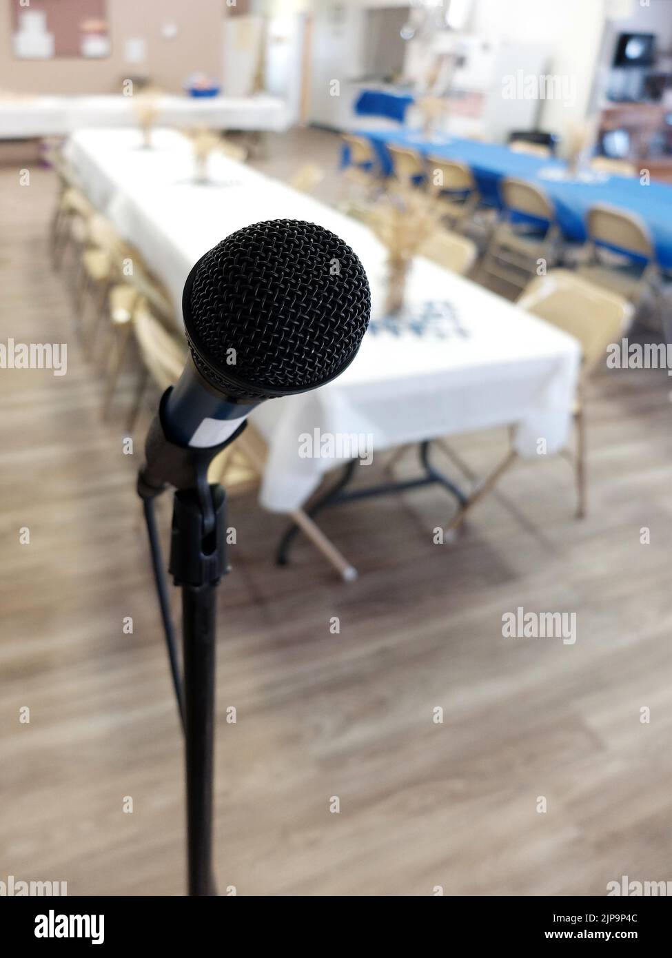 Microphone on a stand in a banquet room with tables and chairs for a ...