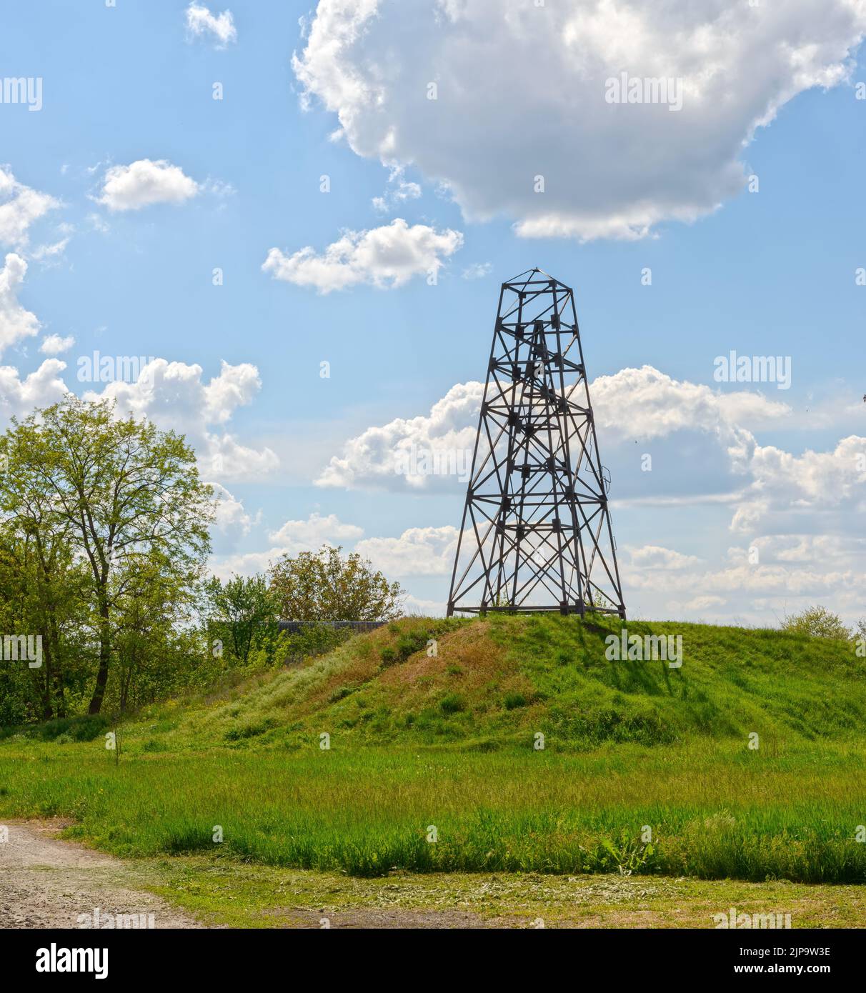 Silhouette of metal geodetic tower is on hillock on cloudy sky ...