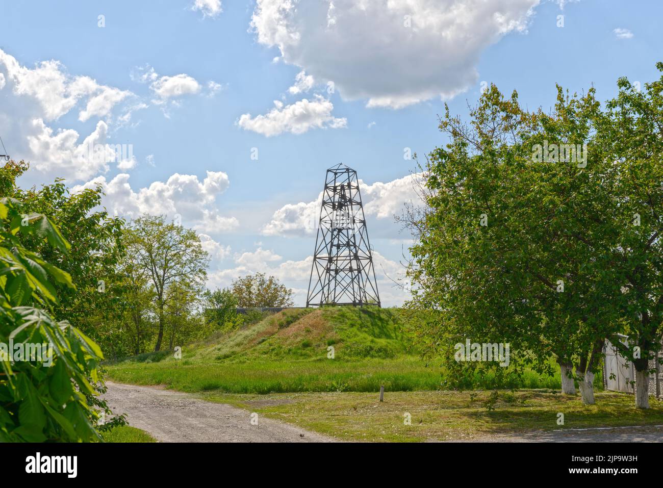 Silhouette of metal geodetic tower is on hillock on cloudy sky ...
