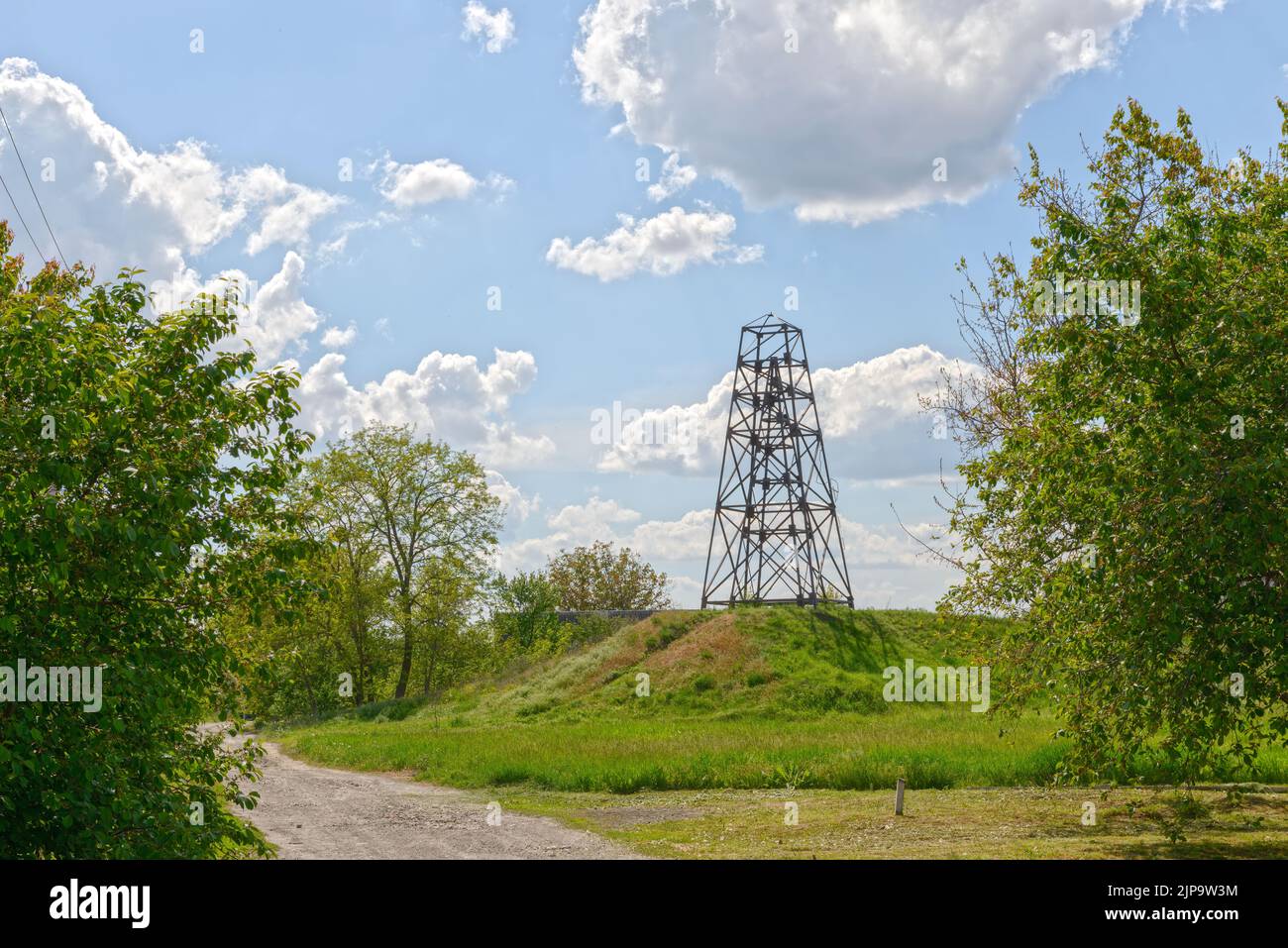 Silhouette of metal geodetic tower is on hillock on cloudy sky ...