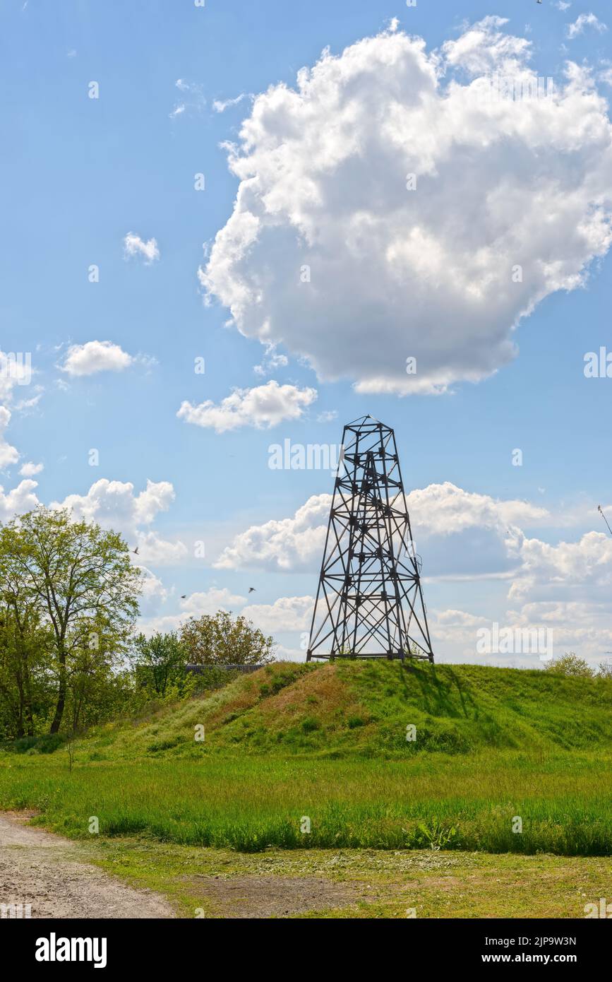 Silhouette of metal geodetic tower is on hillock on cloudy sky ...