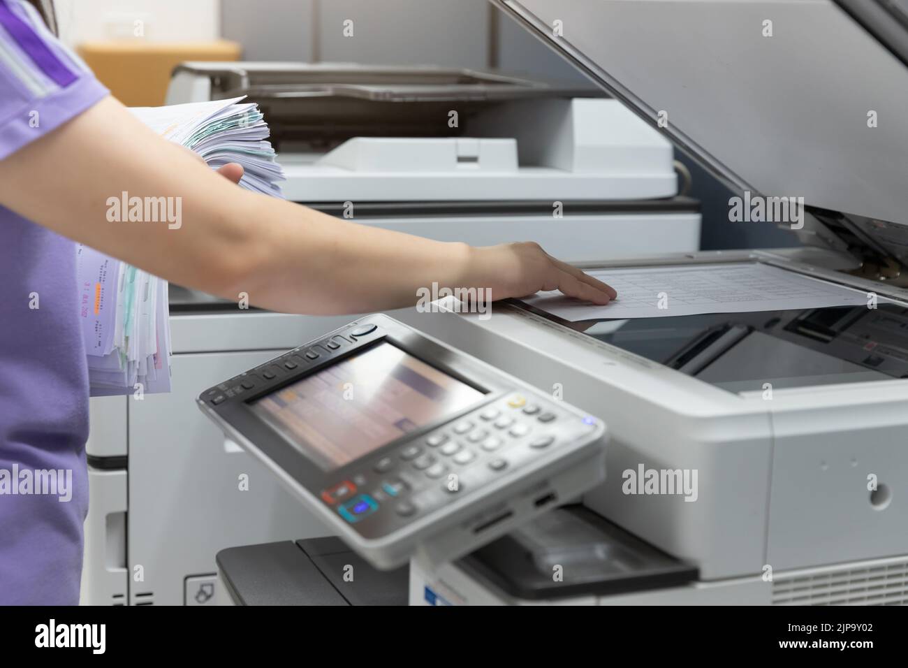 Woman standing and pressing button button on panel of printer, printer ...
