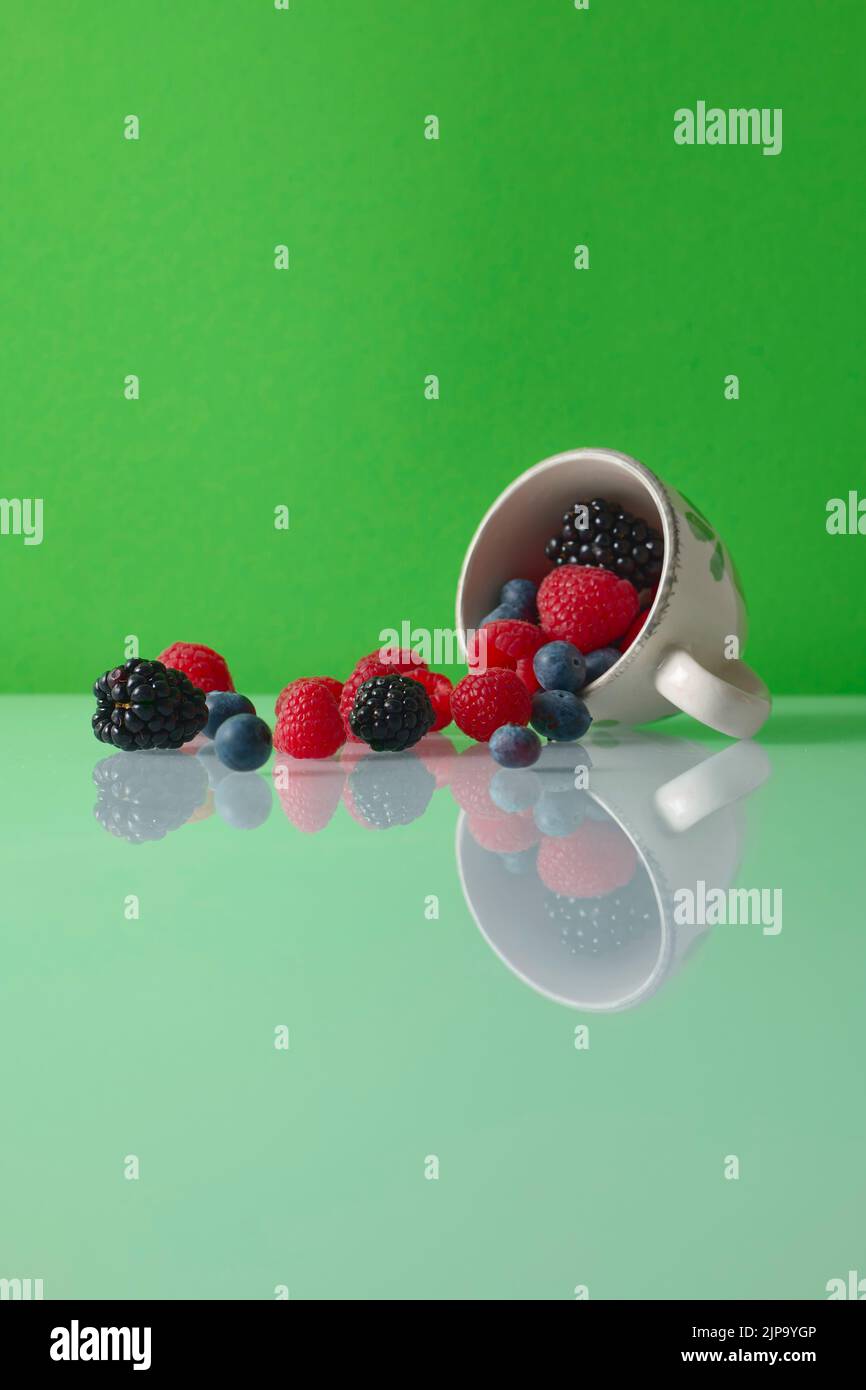 Cup with red fruits on green background with mirror effect Stock Photo ...