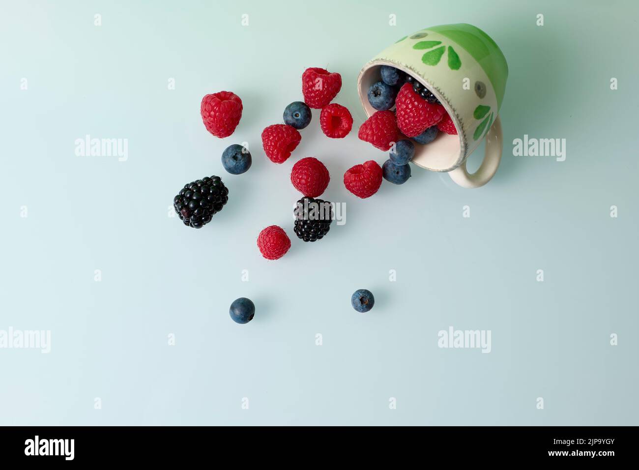 Cup with red fruits on green background with mirror effect Stock Photo ...