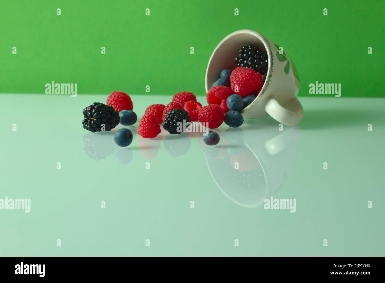 Cup with red fruits on green background with mirror effect Stock Photo ...