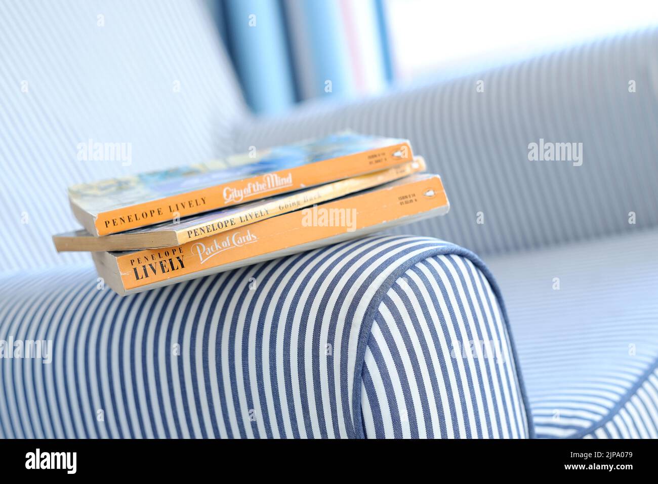 Paperback Books on the arm of a blue stripped chair Stock Photo - Alamy
