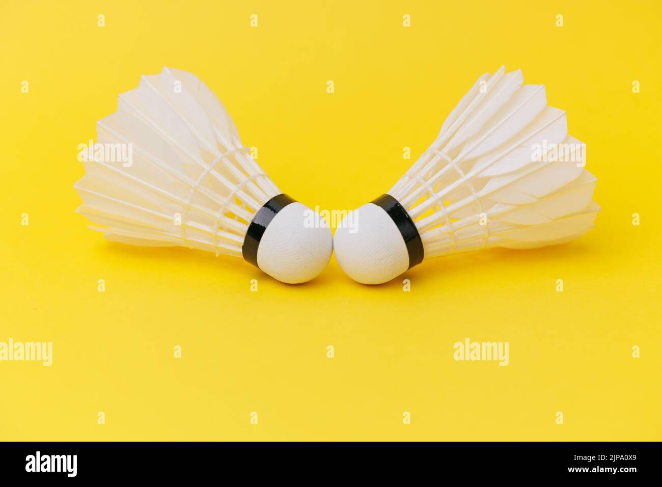 A two badminton shuttles next to each other isolated on a yellow ...