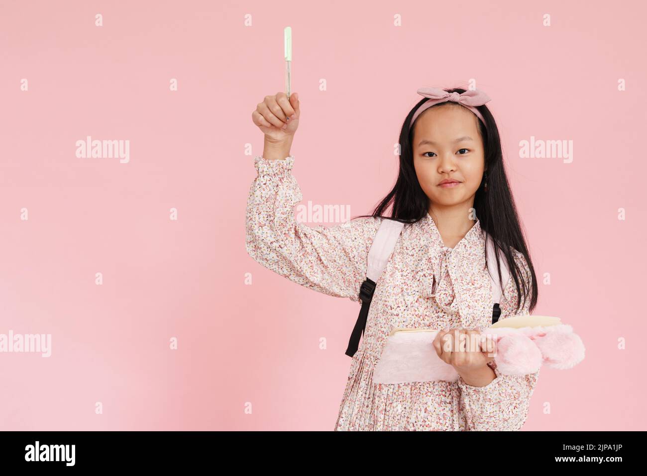 Asian girl wearing dress gesturing while writing down notes isolated ...