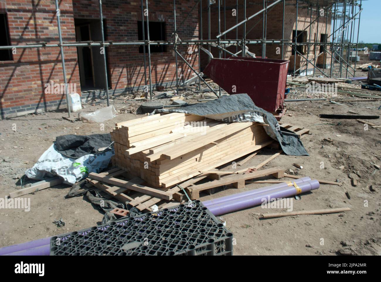 Stack of planks of wood in front of partially constructed house ...