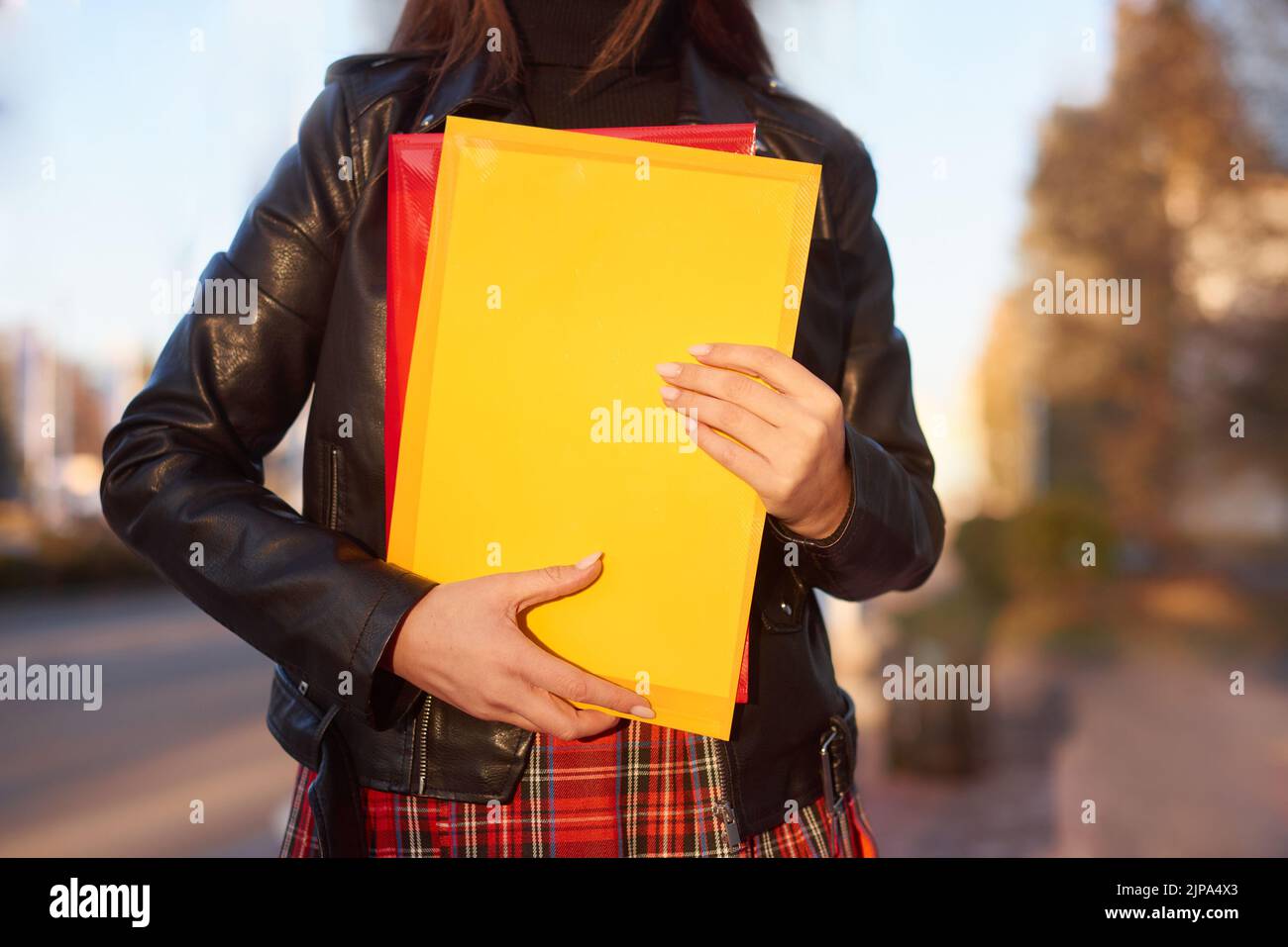 girl student in red skirt in university. woman holds yellow and red ...