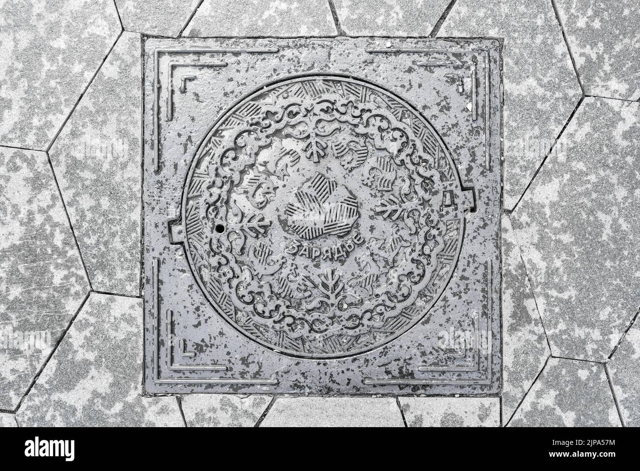 The cover of a decorative sewer manhole on the pavement, with the ...