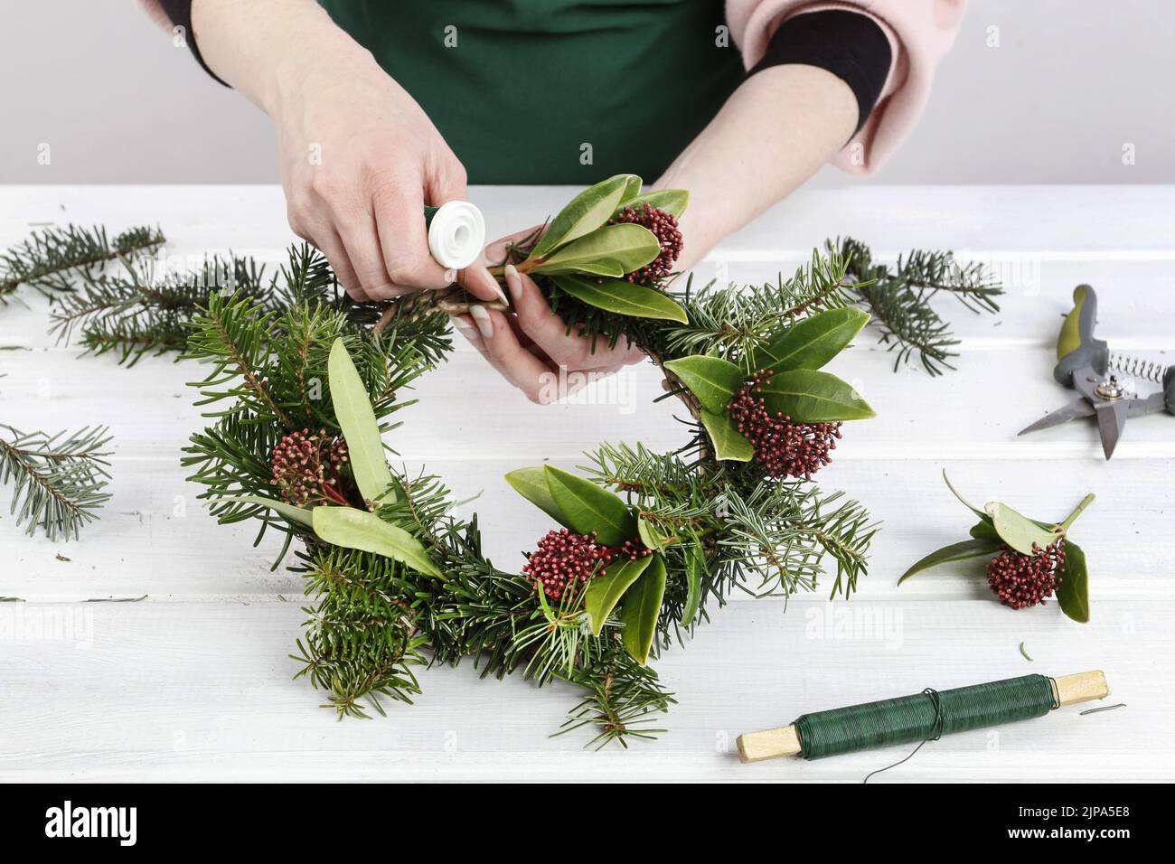Florist at work: woman shows how to make Christmas door wreath made of ...