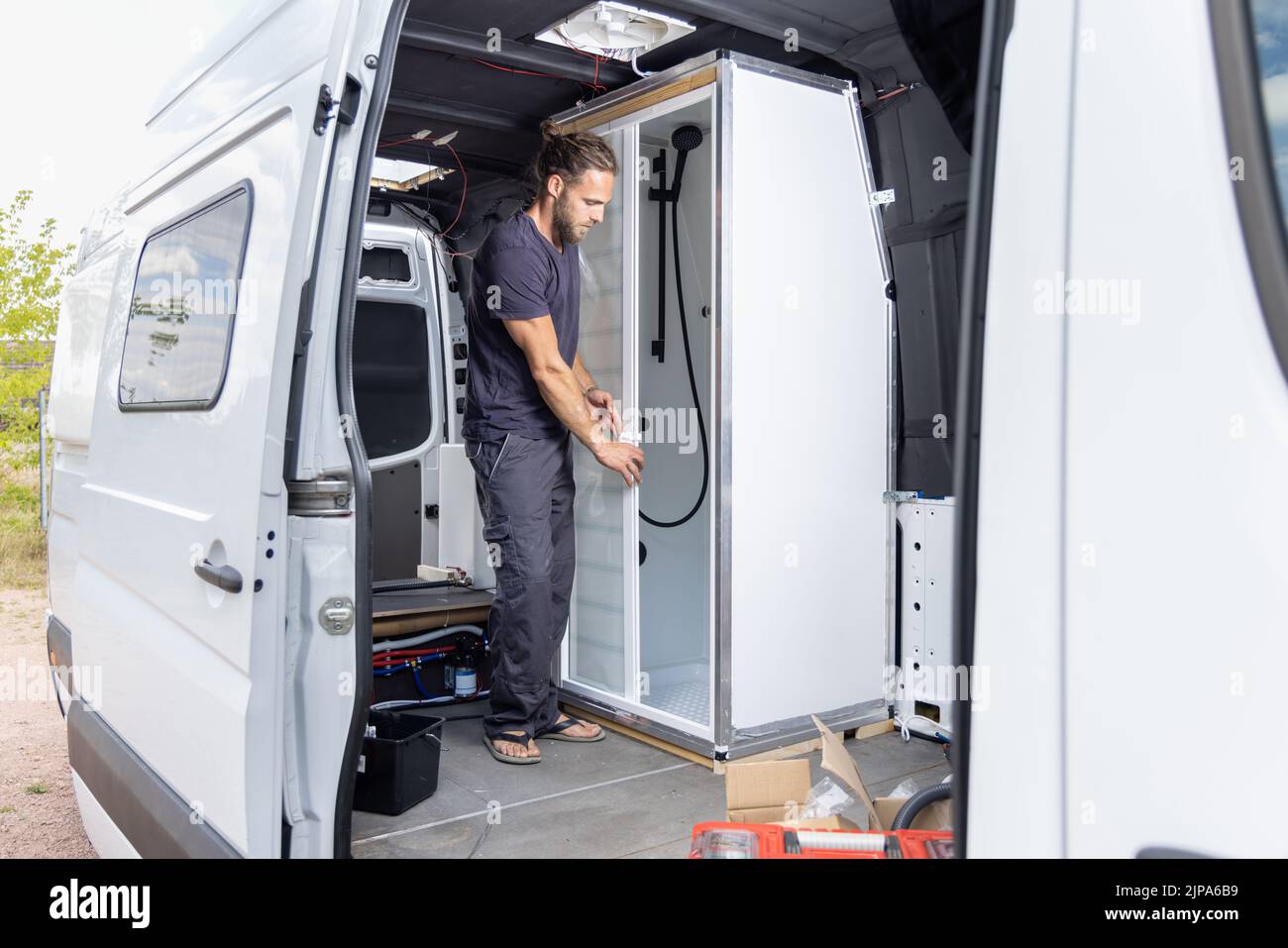 Man installing a shower room inside a camper van Stock Photo - Alamy