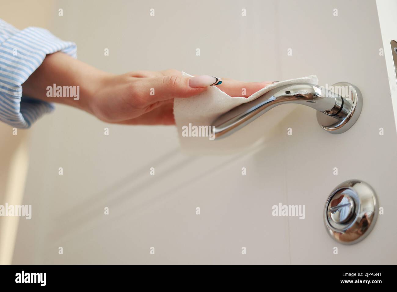 Woman cleaning door handle with antiseptic disinfectant wet wipe. Low ...