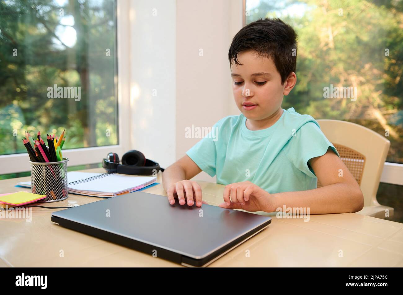 Smart teenage school boy sitting at laptop, getting ready for an online ...