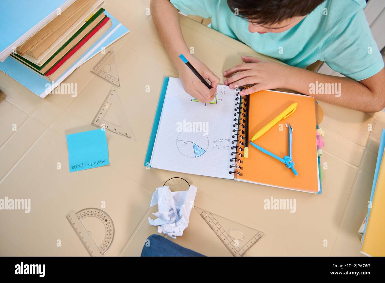 Top view of a schoolchild doing math geometry task on copybook ...