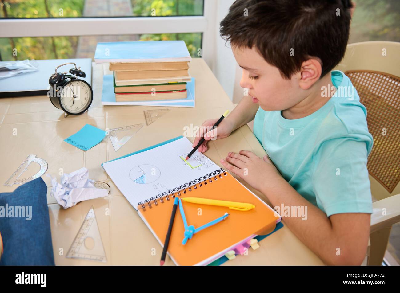 Top view of a concentrated smart Caucasian schoolboy doing geometry ...