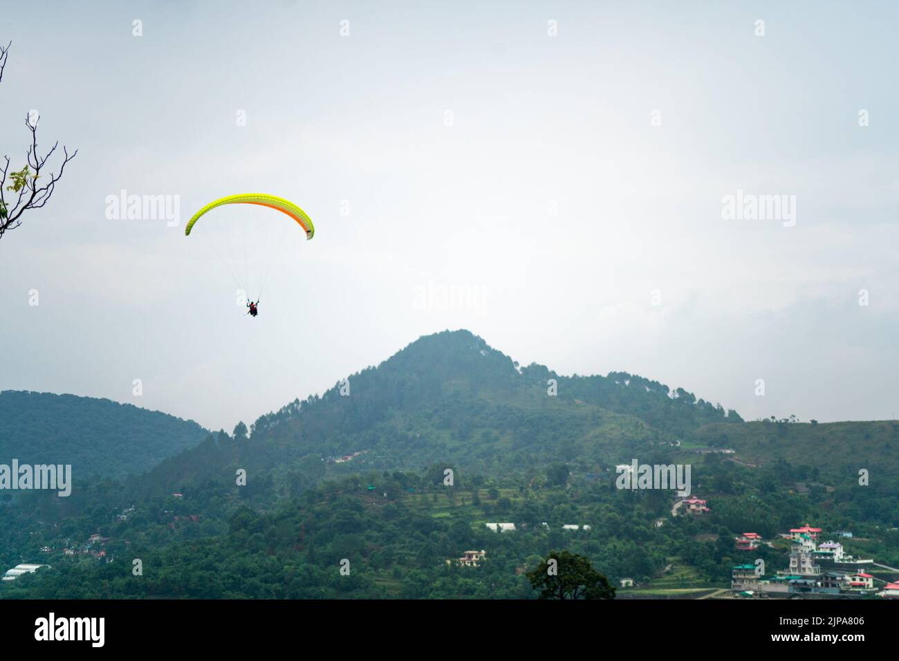 para gliding people with a bright orange yellow glider in the middle of ...