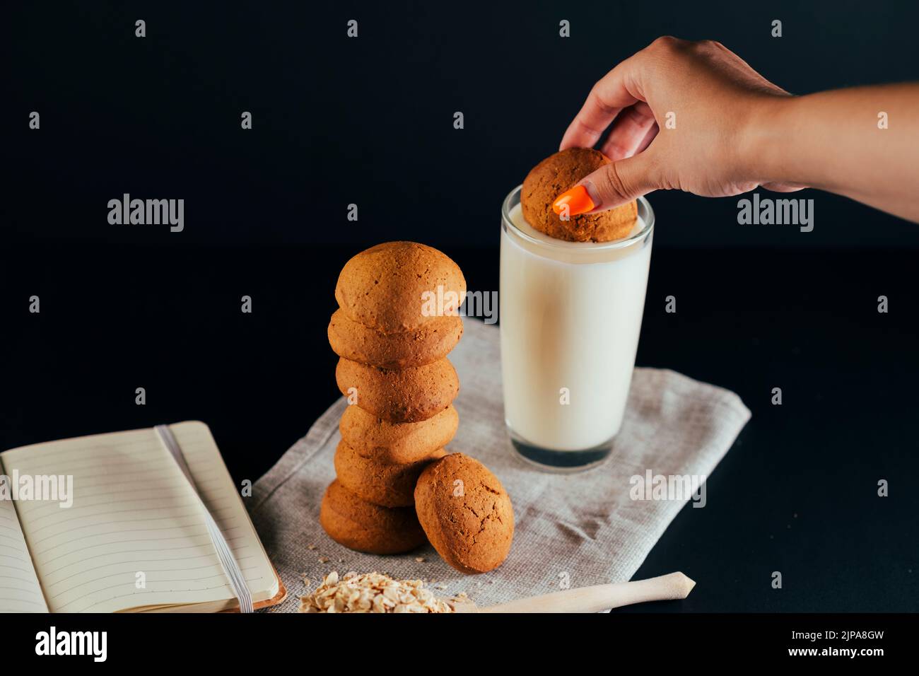 Oatmeal cookies laid out in a stack, a woman's hand soaks cookies in a ...