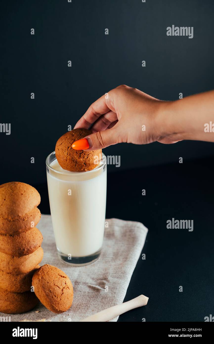 Oatmeal cookies laid out in a stack, a woman's hand soaks cookies in a ...