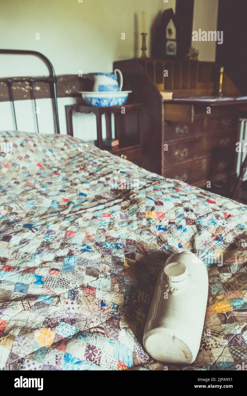 A vintage bedwarmer on an embroidered quilt in a servant's bedroom ...