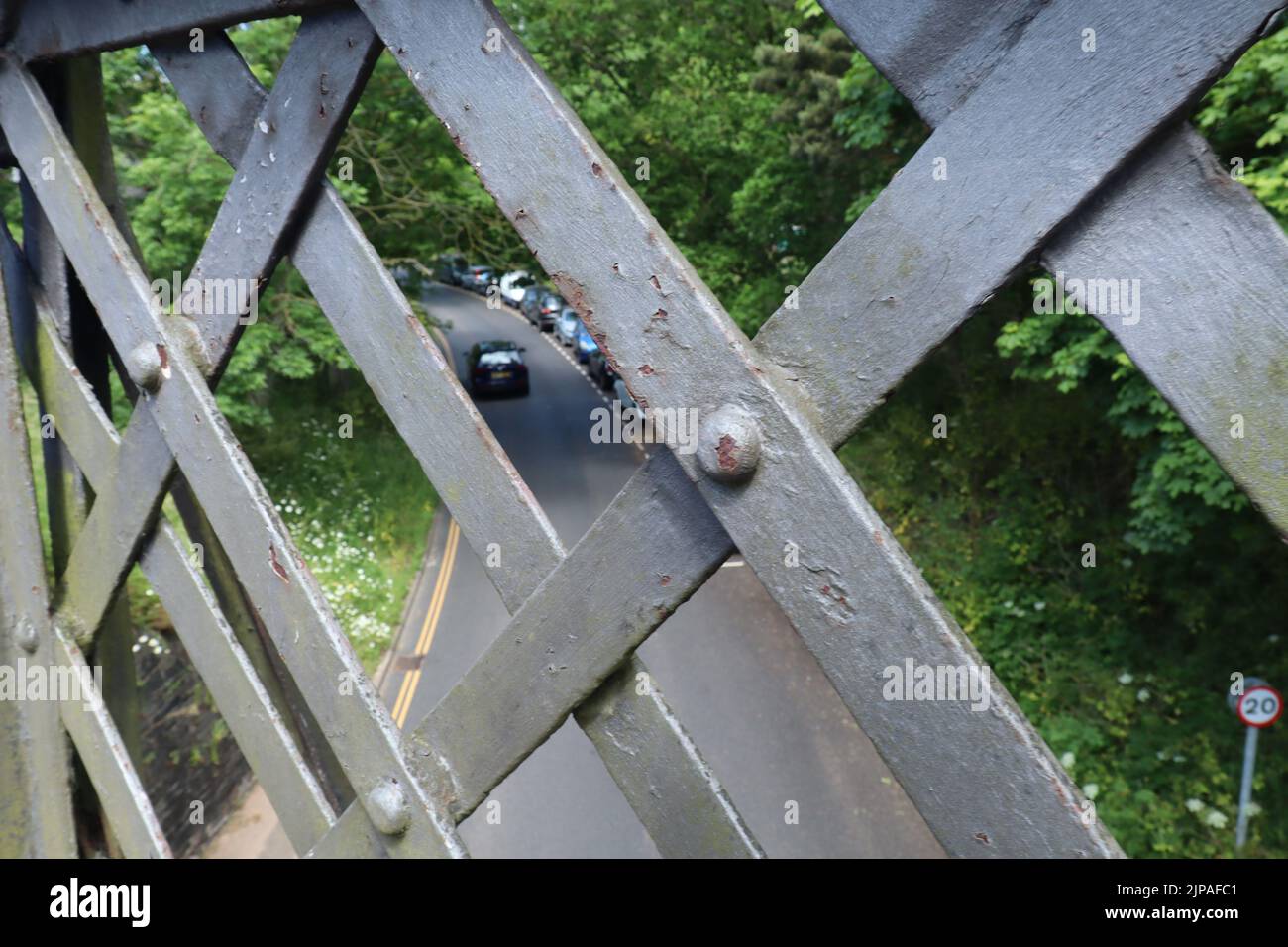A view of the road through a rusty metal lattice bridge in Topsham in ...