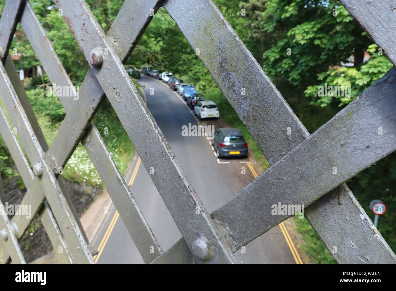 A view of a line of parked cars seen through a rusty metal lattice ...
