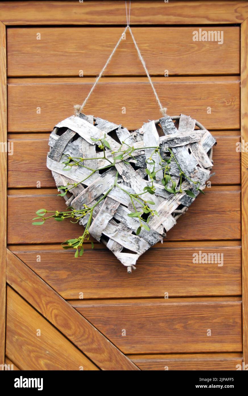 Heart deco made of tree bark with mistletoe branch on door Stock Photo ...