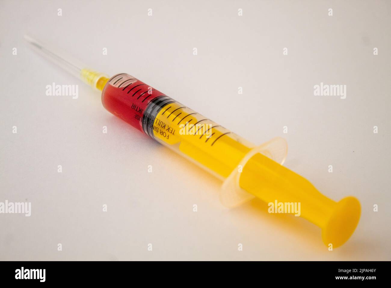 A yellow syringe with blood, isolated white background Stock Photo - Alamy