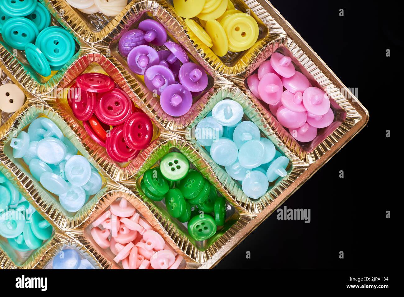 Close-up of a box with a set of multi-colored buttons in plastic cells ...
