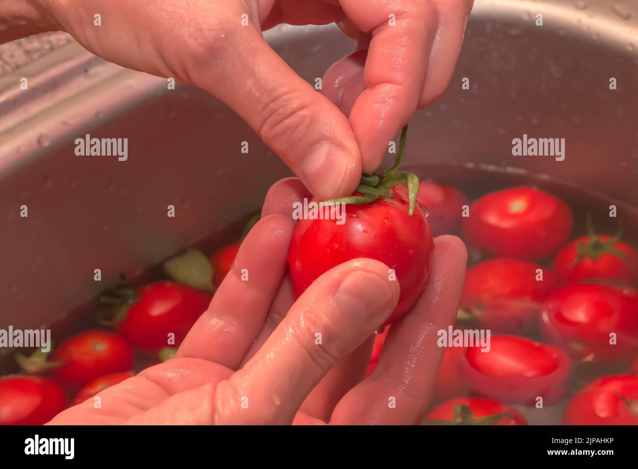 The woman's hands wash the tomatoes and remove the stalks from the ...