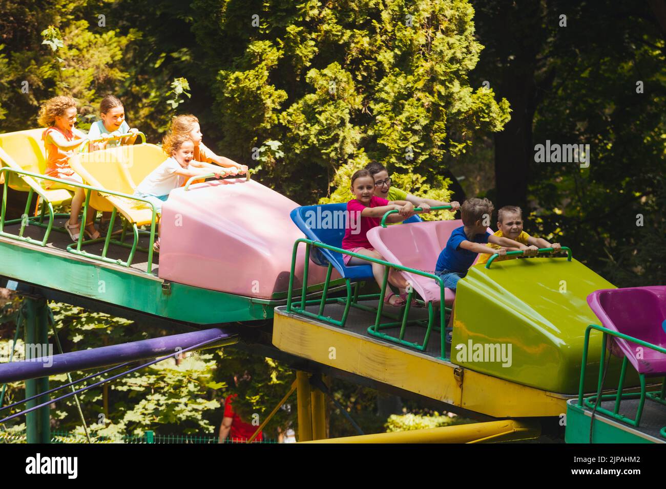 The happy kids on a roller coaster in the amusement park Stock Photo ...