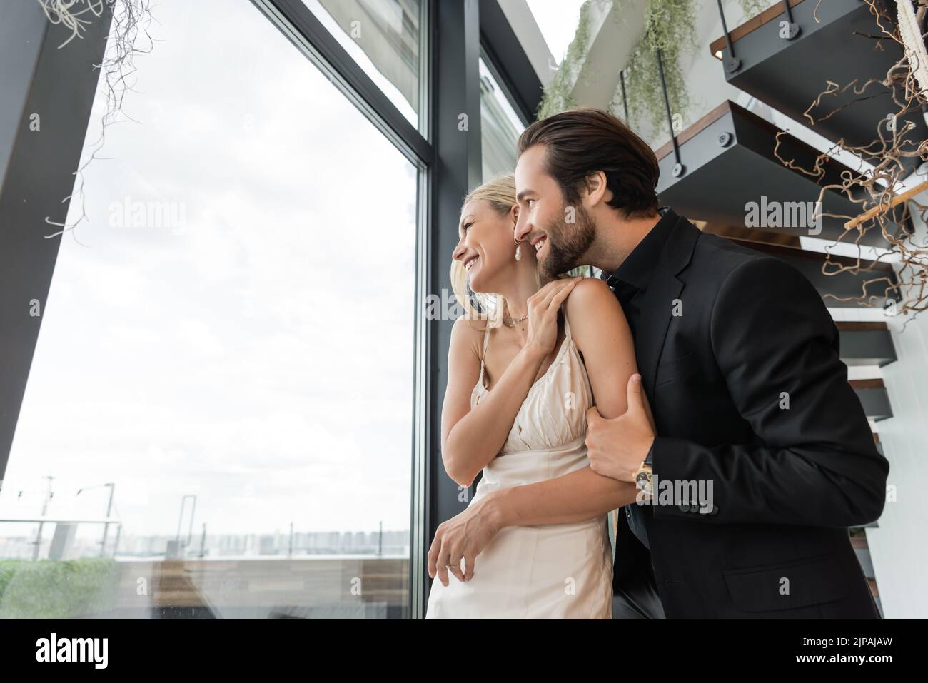 Side view of cheerful romantic couple looking at window in restaurant ...