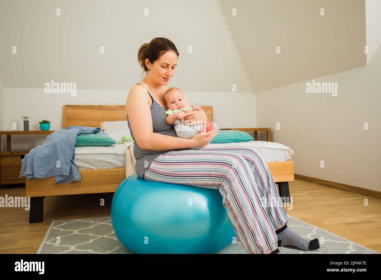 Mother holding and rocking baby sitting on fitball Stock Photo - Alamy