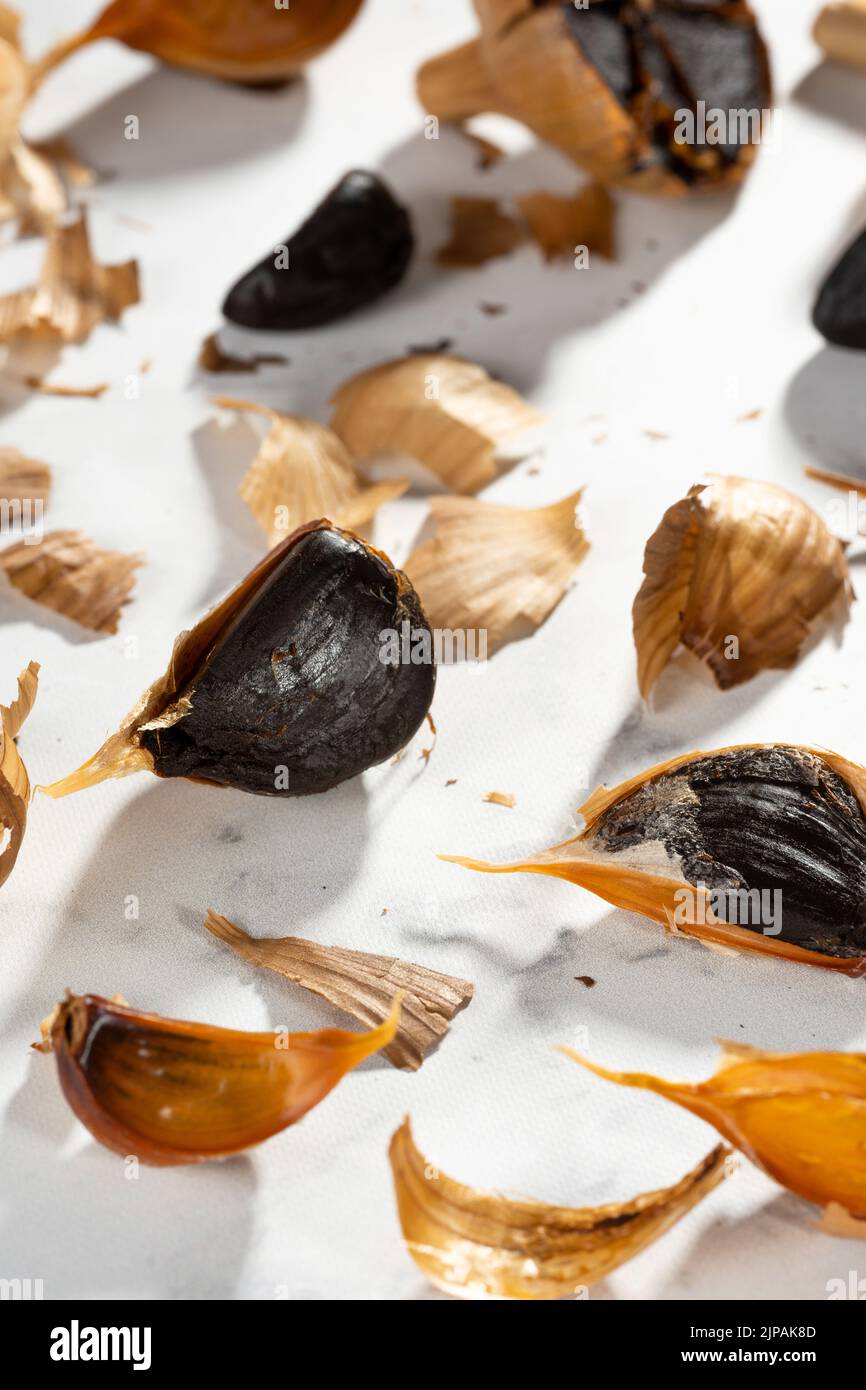 Cloves of fermented garlic lying on a white background. The peel and ...