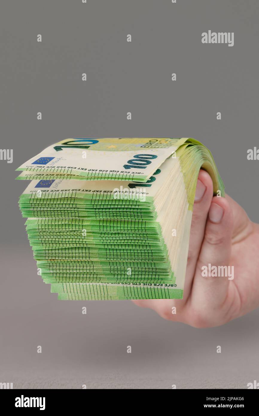 Large stack of euros in hand. Banknotes of 100 euros in a male hand on ...