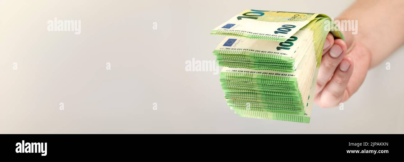 Stack of euro bills in hand. A large stack of 100 euro banknotes in a ...