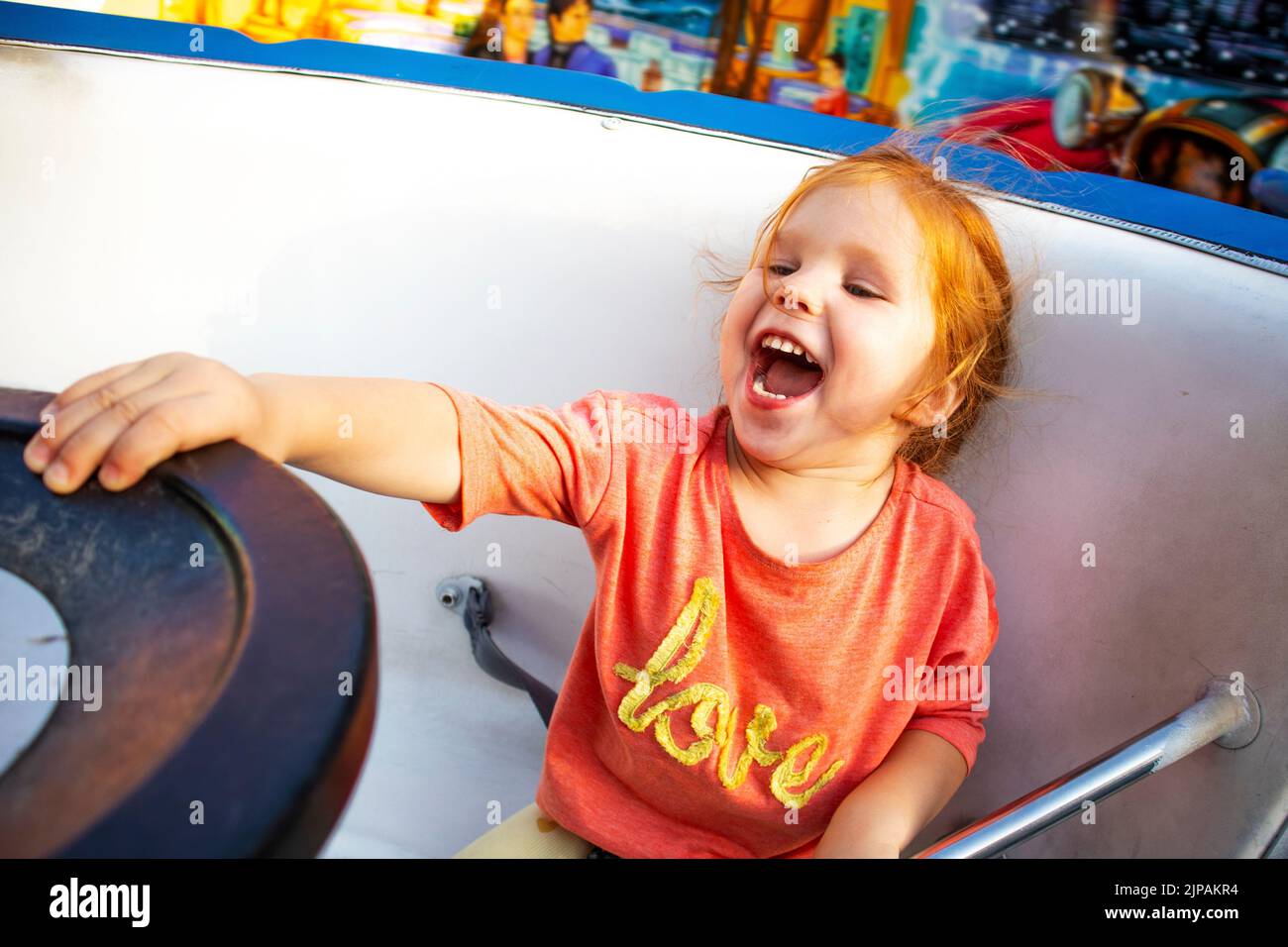 a little red-haired girl on the attraction laughs and enjoys the ride ...