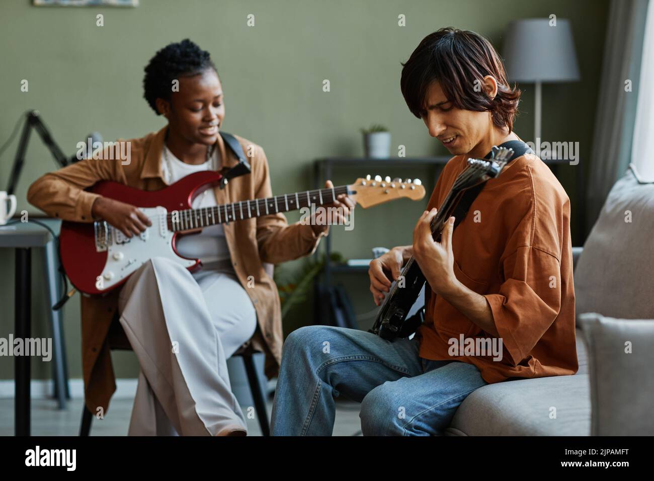 Portrait of two young musicians playing guitars together and singing in ...