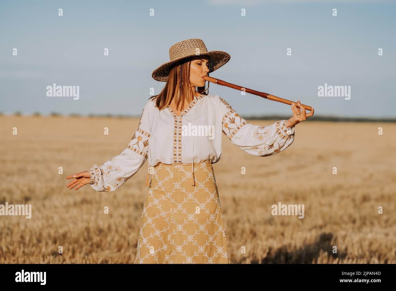 Rural woman plays on wooden flute - ukrainian telenka, tylynka in wheat ...