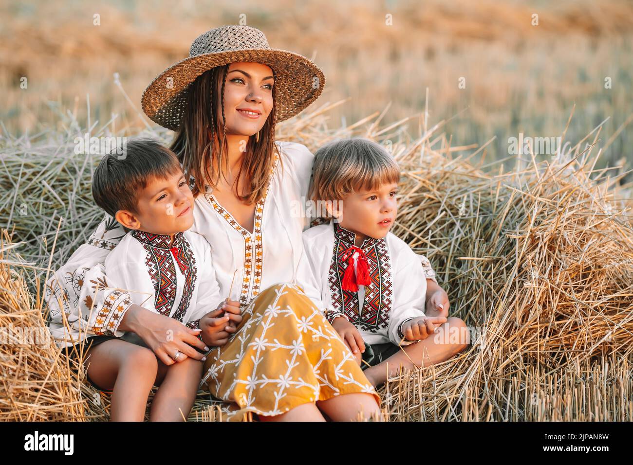 Ukrainian boys and mother sitting together on wheat in field after ...